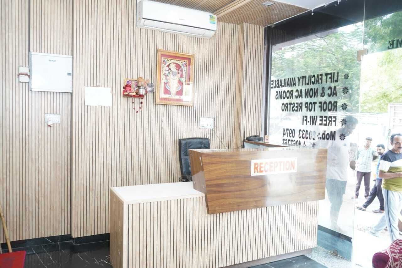 Um balcão de recepção com uma placa que diz 'RECEPTION', um quadro na parede e uma janela com vista para pessoas do lado de fora.