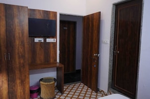 Quarto com armários de madeira, televisão, porta e chão em azulejos.