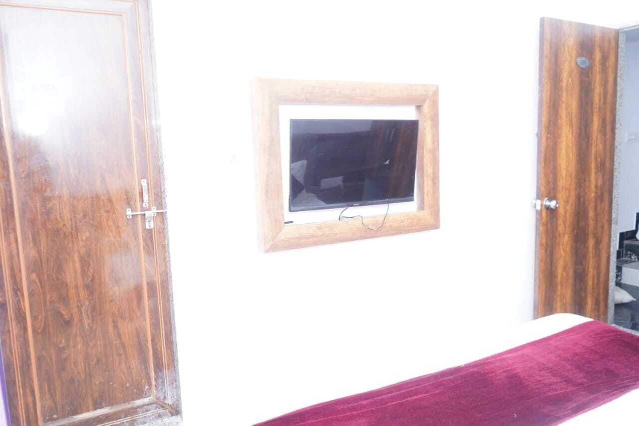 Um quarto com porta de madeira, janela com moldura de madeira e cama com manta vermelha.