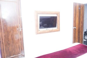 Um quarto com porta de madeira, janela com moldura de madeira e cama com manta vermelha.