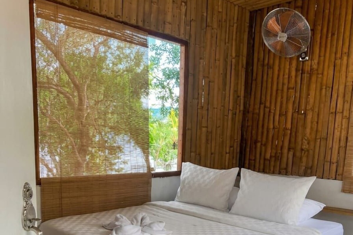 Quarto com cama grande, ventilador e janela com persianas.