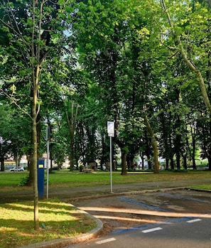 Um parque com um sinal de estacionamento, árvores e uma trilha.