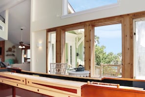 Quarto com um banco de madeira, uma mesa e uma grande janela com vista para vegetação.