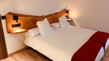 Cama com cabeceira de madeira, roupa de cama branca e duas luminárias laterais.