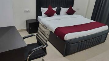 Quarto de hotel com uma cama, uma escrivaninha e uma cadeira.