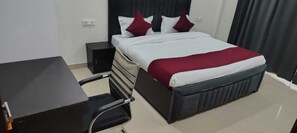 Quarto de hotel com uma cama, uma escrivaninha e uma cadeira.