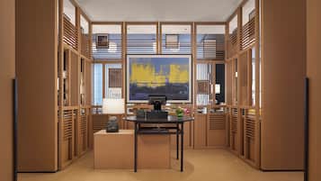 Um interior moderno com uma mesa central, uma grande obra de arte emoldurada e estantes embutidas.