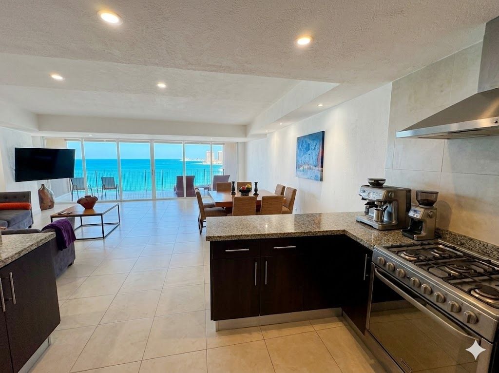 Cozinha moderna com uma ilha grande, sala de jantar com vista e televisão de tela plana na parede.