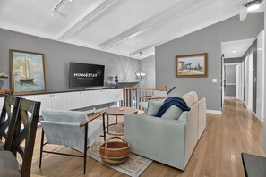 Uma sala de estar moderna com um sofá, mesa de centro e televisão na parede.