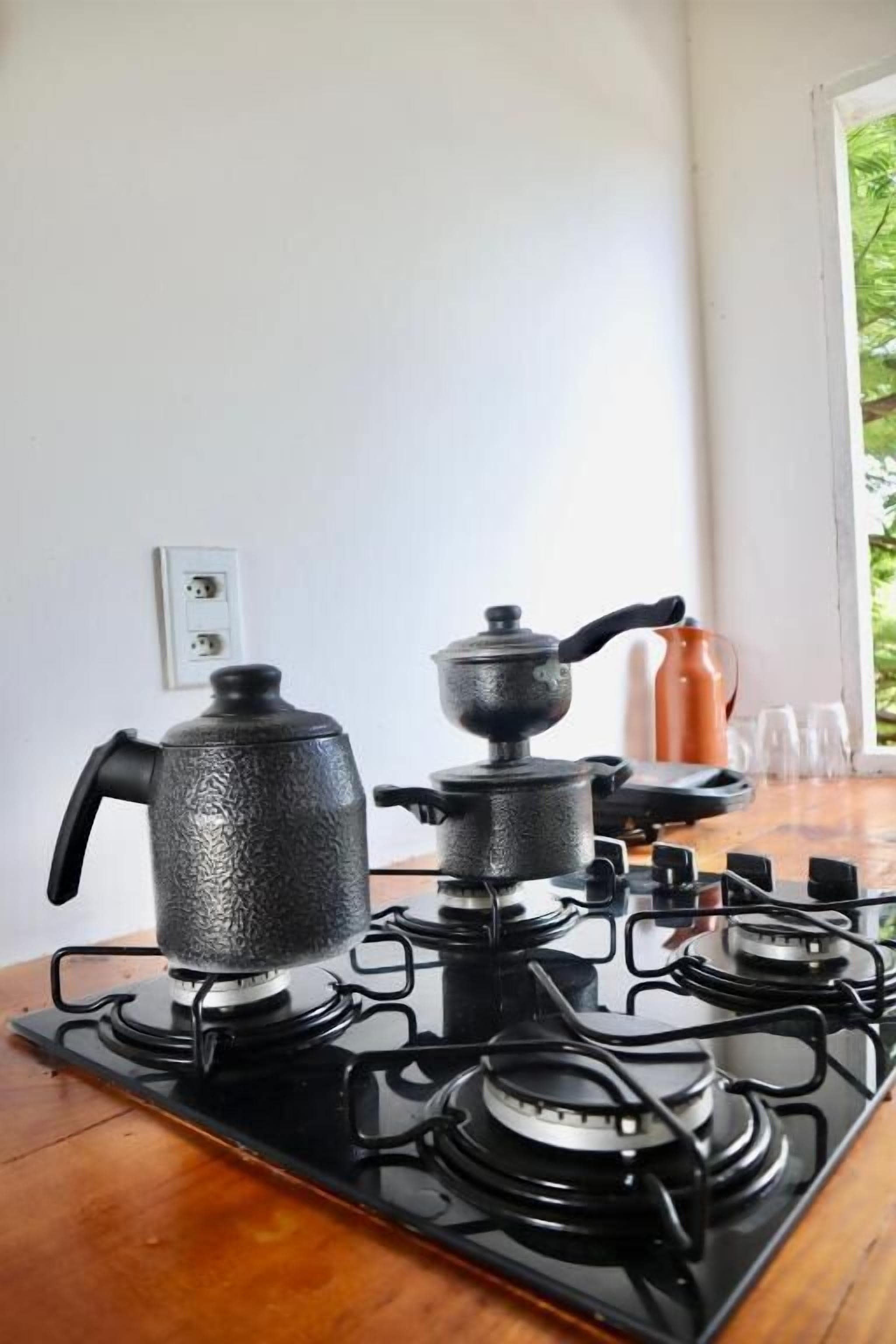 Uma cozinha com fogão a gás, chaleira e panela sobre o balcão.