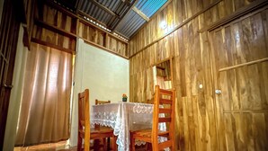 Um quarto com paredes de madeira, uma mesa com toalha rendada e ladrilhos com padrão.