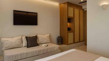 Quarto moderno com cama, sofá, televisão e guarda-roupa.
