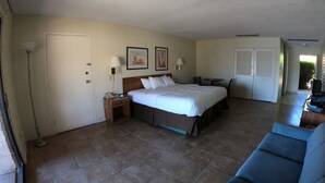 Quarto de hotel com cama, mesa de cabeceira, abajur e uma cadeira.