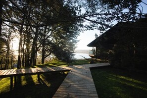Um deck de madeira leva a um edifício com vista para um corpo de água.