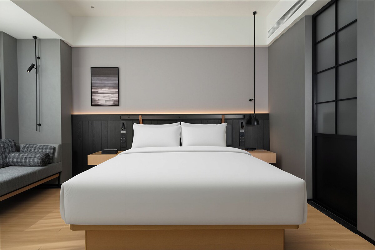 Quarto moderno com cama grande, mesas de cabeceira, obra de arte na parede e armário embutido.