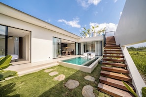 Uma casa moderna com piscina, escadaria de madeira e gramado.