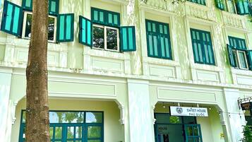 Um edifício com várias janelas e uma placa com a inscrição 'Sweet House PHU QUOC'.
