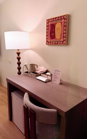 Uma pequena mesa com uma luminária, uma caixa de lenços e uma placa de boas-vindas.