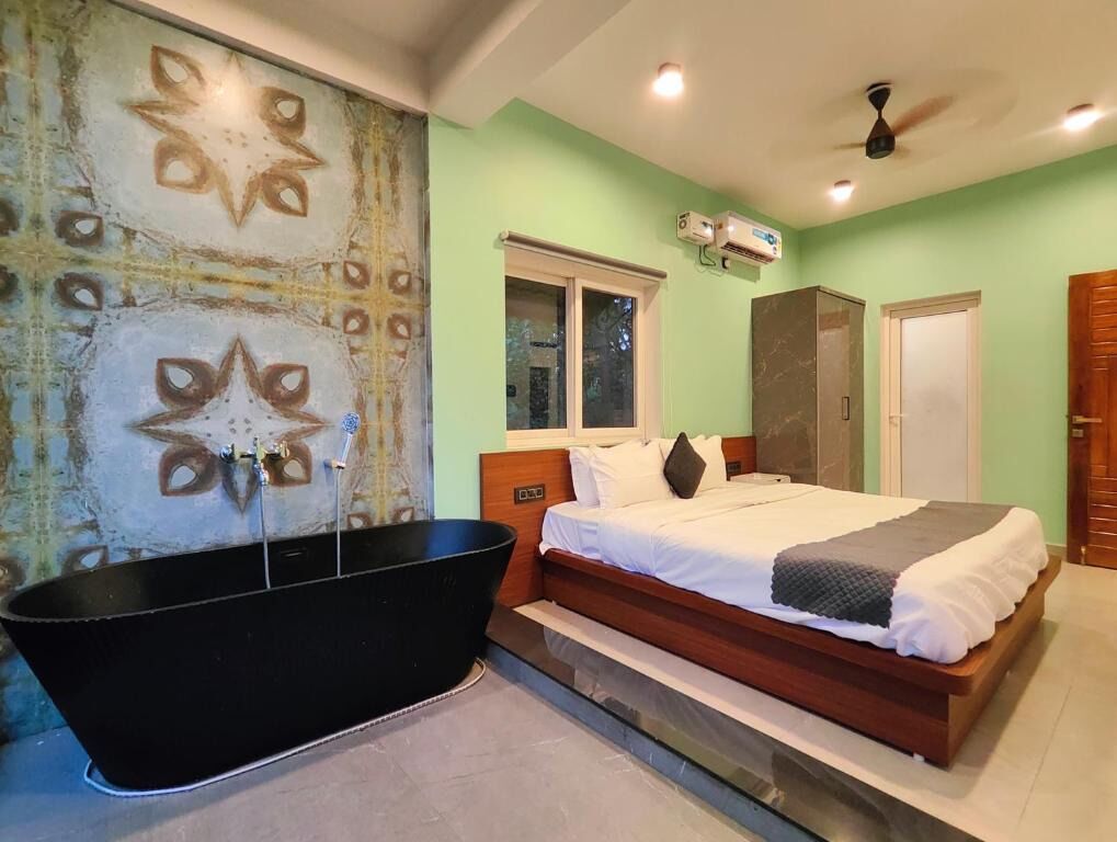Quarto com uma banheira grande, uma cama com roupa de cama branca e uma janela.