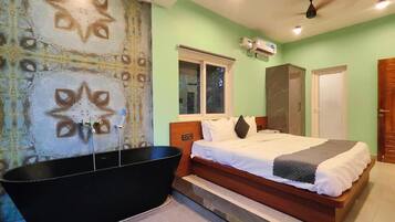 Quarto com uma banheira grande, uma cama com roupa de cama branca e uma janela.