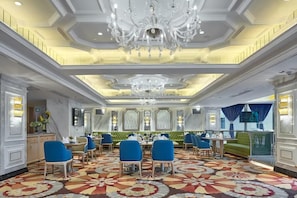 Um hall de hotel com um lustre imponente, várias áreas de estar e um tapete estampado.