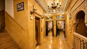 Um hall imponente com uma escadaria de mármore, teto ricamente decorado e um candelabro.