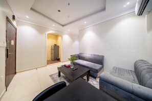 Uma sala de estar moderna com um sofá, uma mesa de centro e uma mesinha com um vaso e um controle remoto.