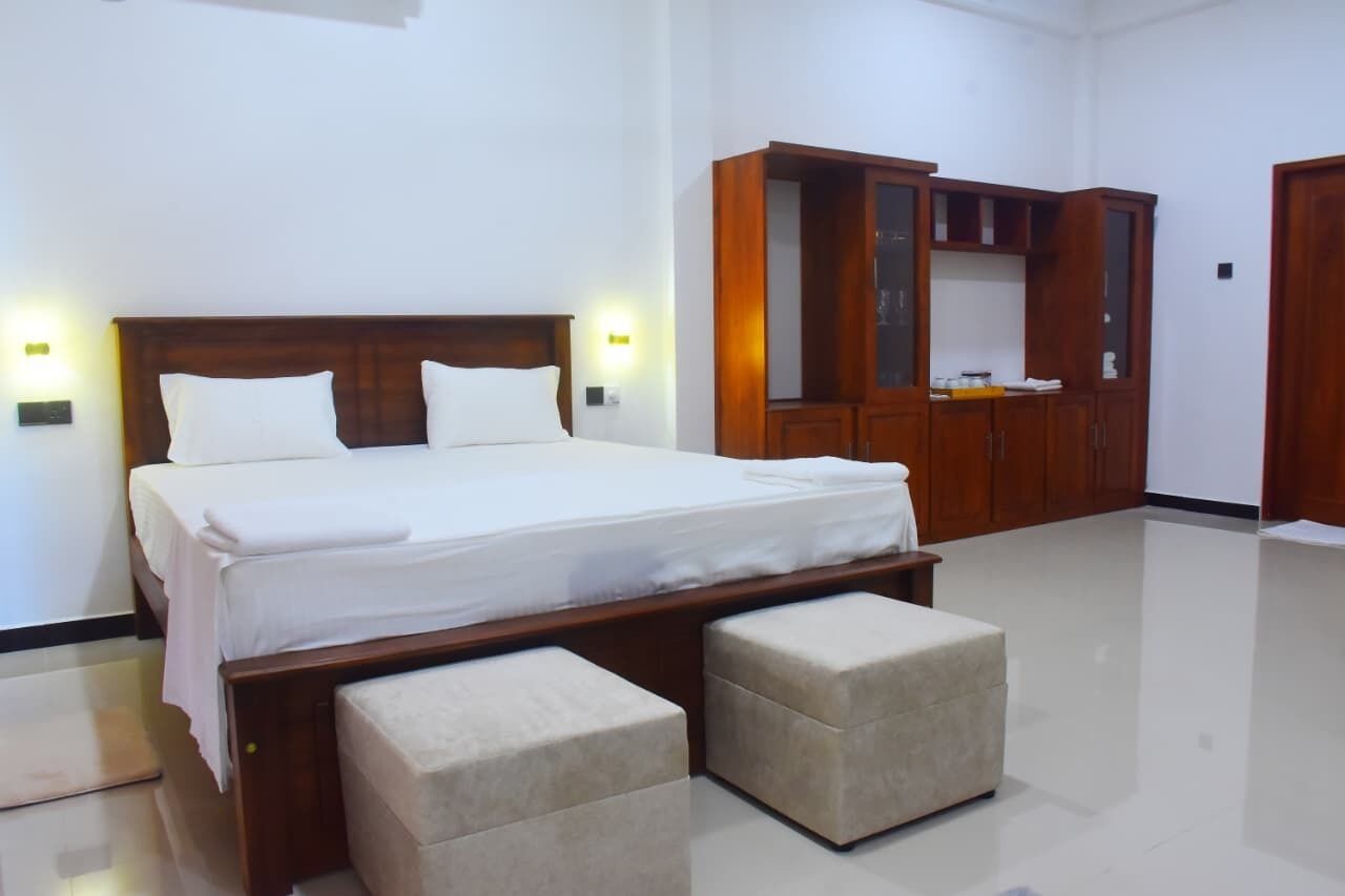 Quarto de hotel com cama, guarda-roupa e um banco.
