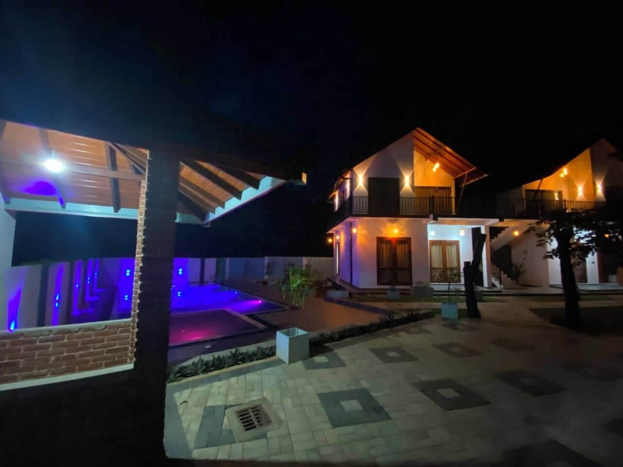 Um pátio com piscina, área de estar coberta e um edifício com varanda.
