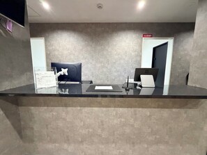Uma receção com computador, telemóvel e porta-canetas.