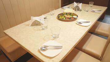 Mesa posta com pratos, talheres, copos e um prato central.