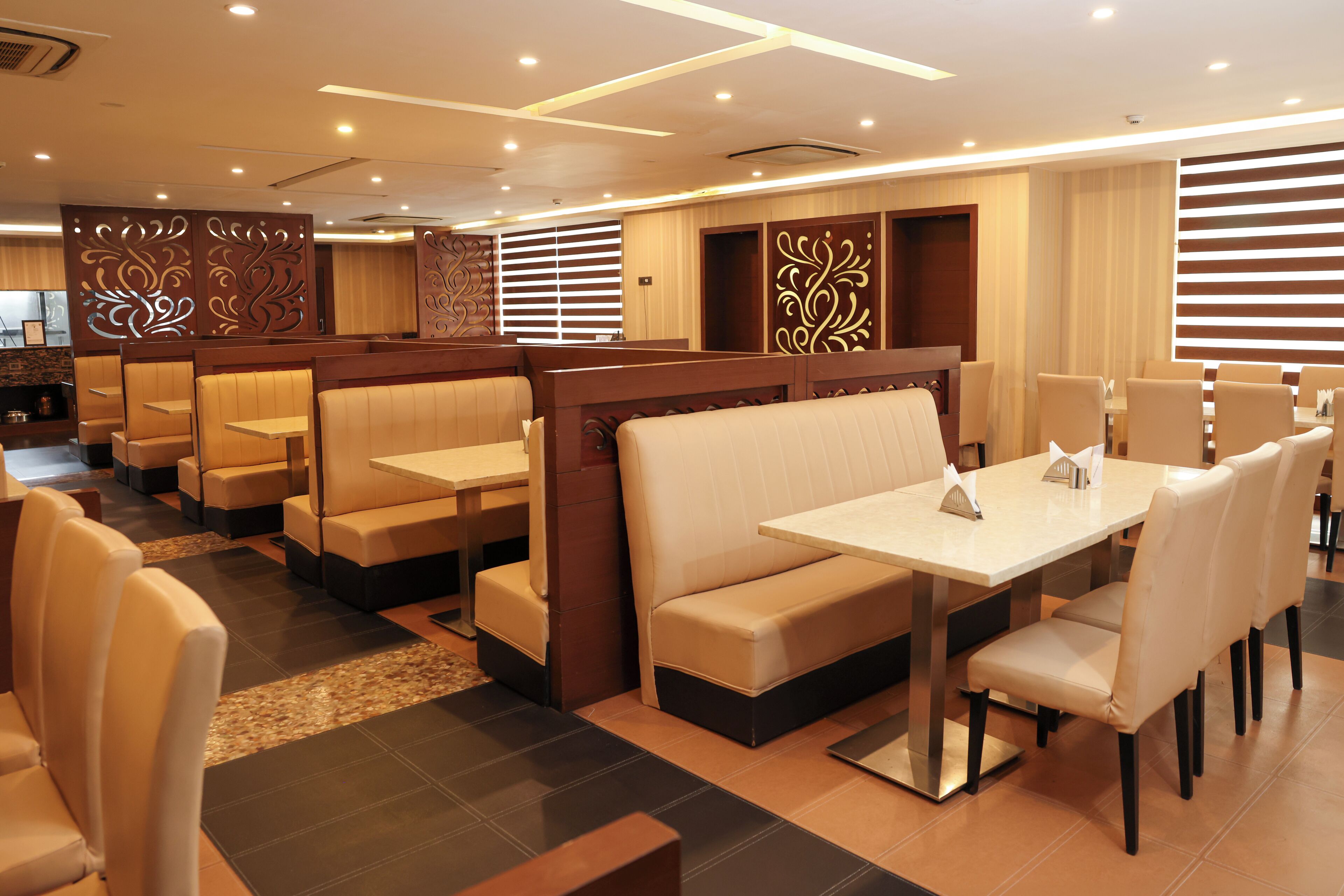 Restaurante com assentos em cabines e mesas, com design moderno e detalhes em madeira, e um divisório de parede estampado.