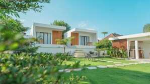 Uma casa moderna de dois andares, com um gramado bem cuidado e um espaço de varanda.