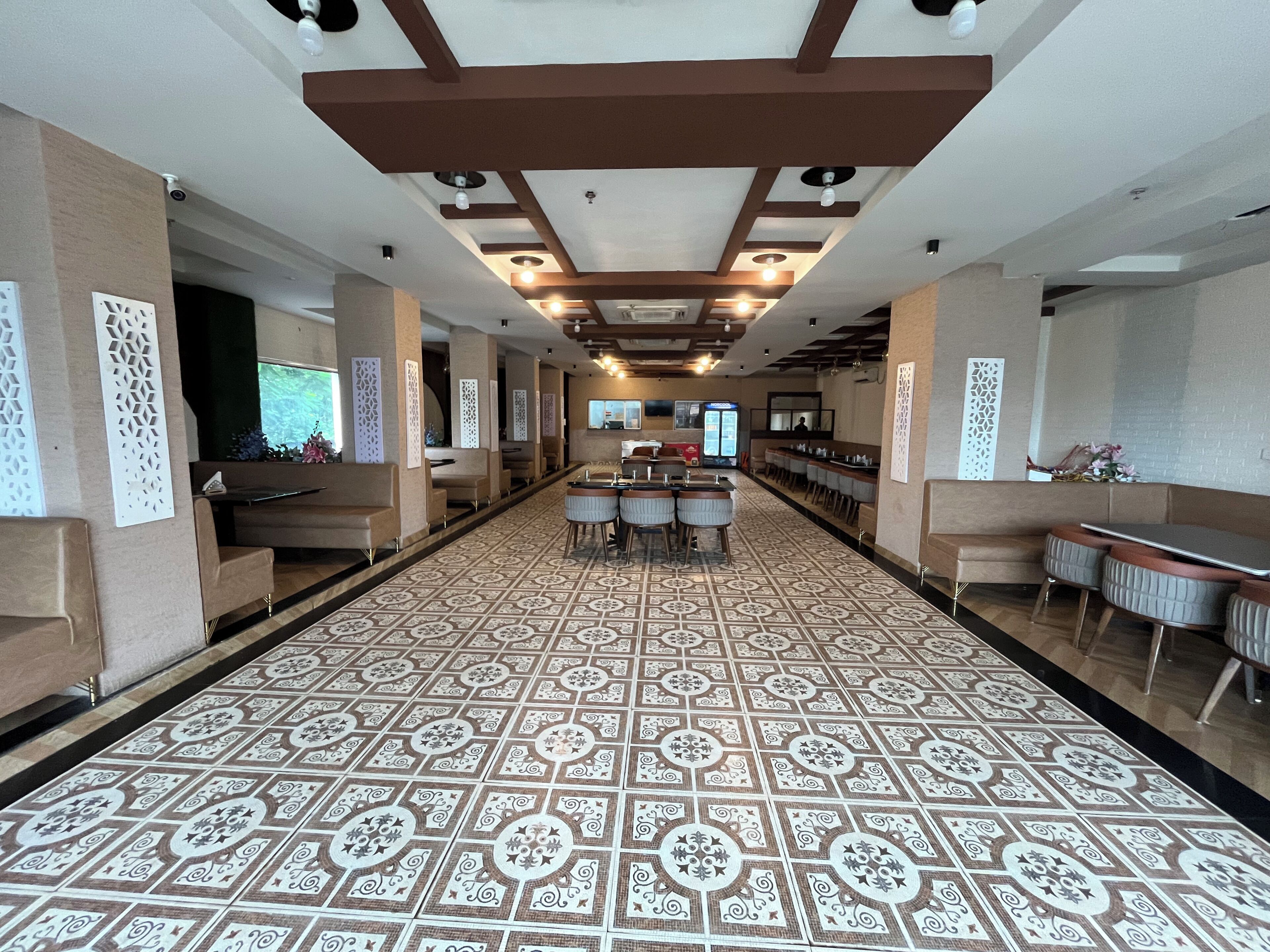 Um amplo hall de hotel com piso estampado, áreas de estar e um bar central.