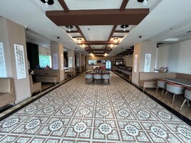 Um amplo hall de hotel com piso estampado, áreas de estar e um bar central.