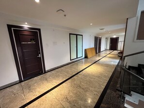 Um corredor com piso de mármore, portas e escadas.