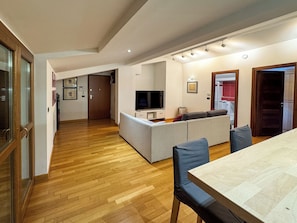 Uma sala de estar moderna com um sofá, uma TV e uma mesa de jantar.