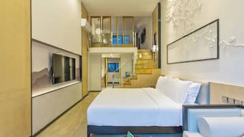 Quarto de hotel com cama, sofá, televisão, escada e varanda.