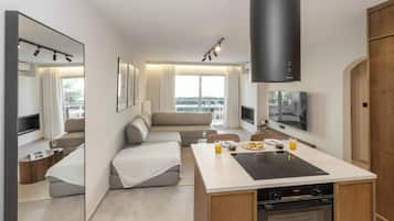Uma cozinha moderna com uma ilha central, área de jantar com sofá e uma grande janela com vista.