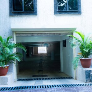Entrada de um edifício com caminho acessível e plantas em vasos de ambos os lados.