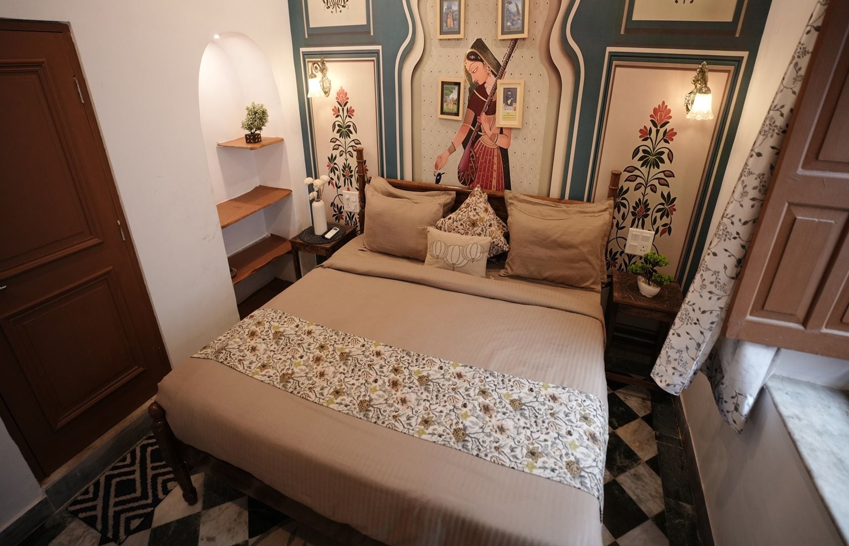 Um quarto com cama, mesas de cabeceira, luminária na parede e um painel decorativo.