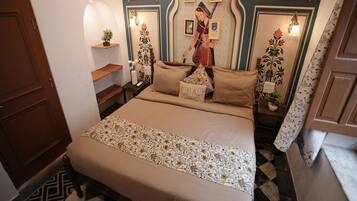 Um quarto com cama, mesas de cabeceira, luminária na parede e um painel decorativo.