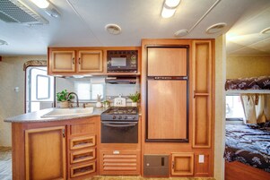 Cozinha compacta de RV com fogão, pia e micro-ondas.