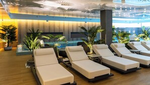 Uma área interna de piscina moderna com espreguiçadeiras e plantas em vasos.