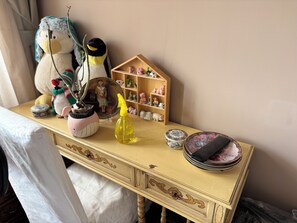 Uma mesa com uma maquete de casa, um brinquedo de pelúcia, um borrifador e pratos decorativos.