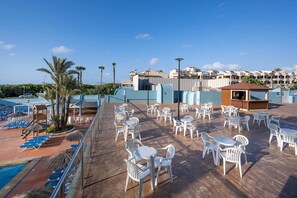 Uma área de piscina no terraço com espreguiçadeiras, mesas e guarda-sóis.