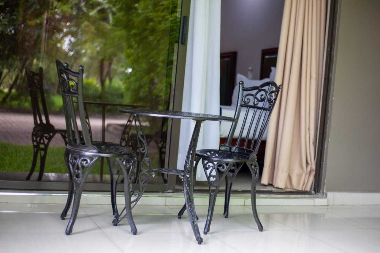 Quarto com porta de vidro que dá para um jardim, uma mesa com cadeiras e vista para árvores lá fora.