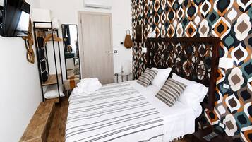 Quarto de hotel com uma cama grande, televisão, guarda-roupa e parede estampada.