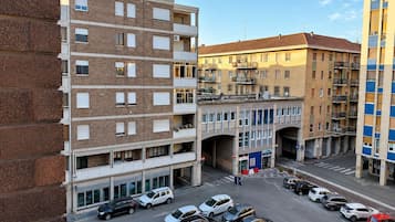 Um estacionamento com vários andares, com diversos carros estacionados, um edifício com varandas e um céu claro.