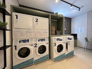 Uma área de lavandaria com máquinas de lavar numeradas e placas de instrução.